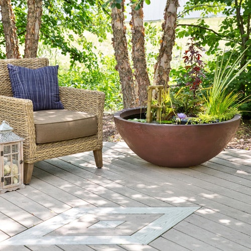 round raised pond on sunny deck next to rattan chair and lantern